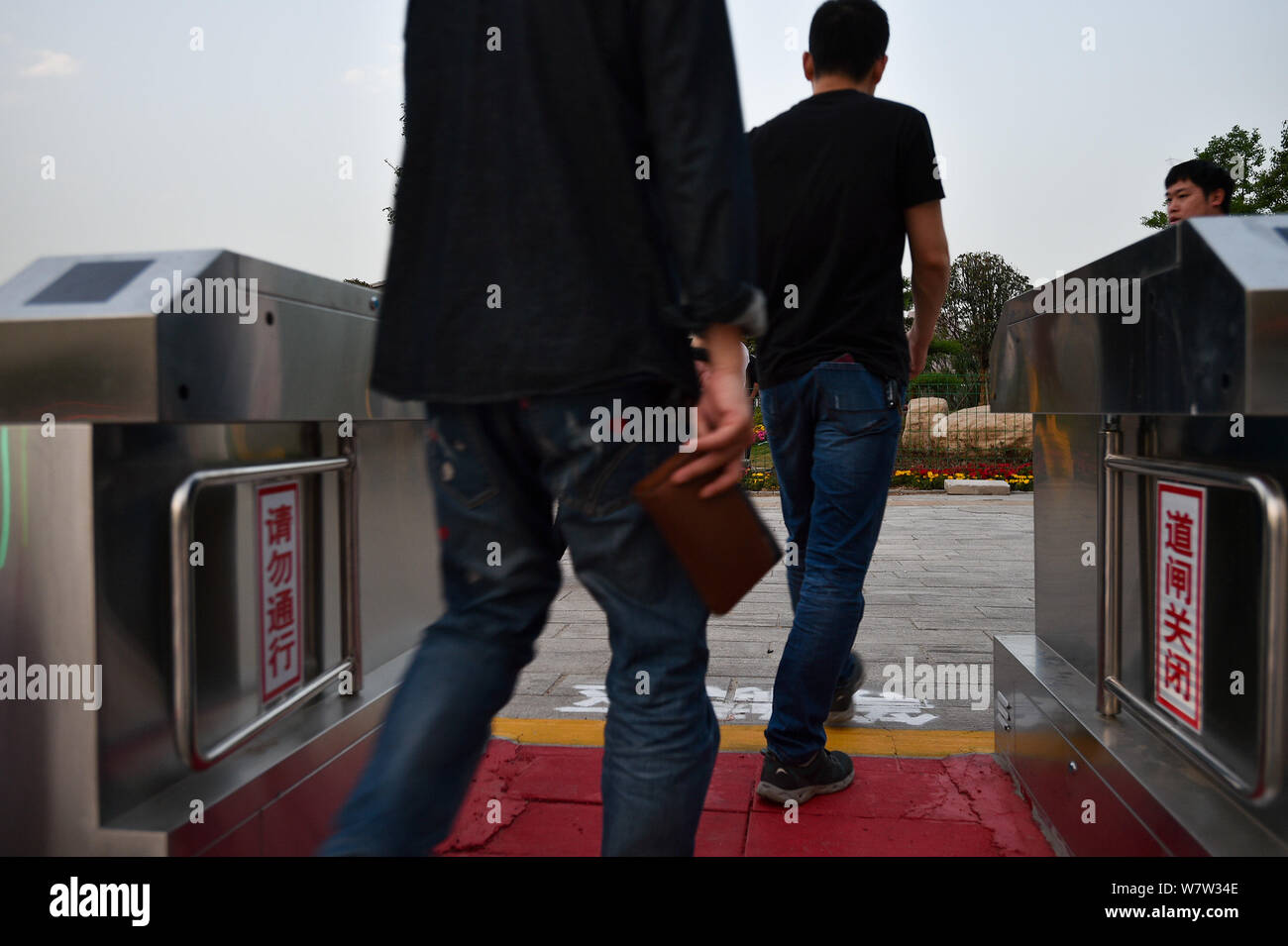 Pedestrians walk through newly installed crosswalk gates, which shut ...