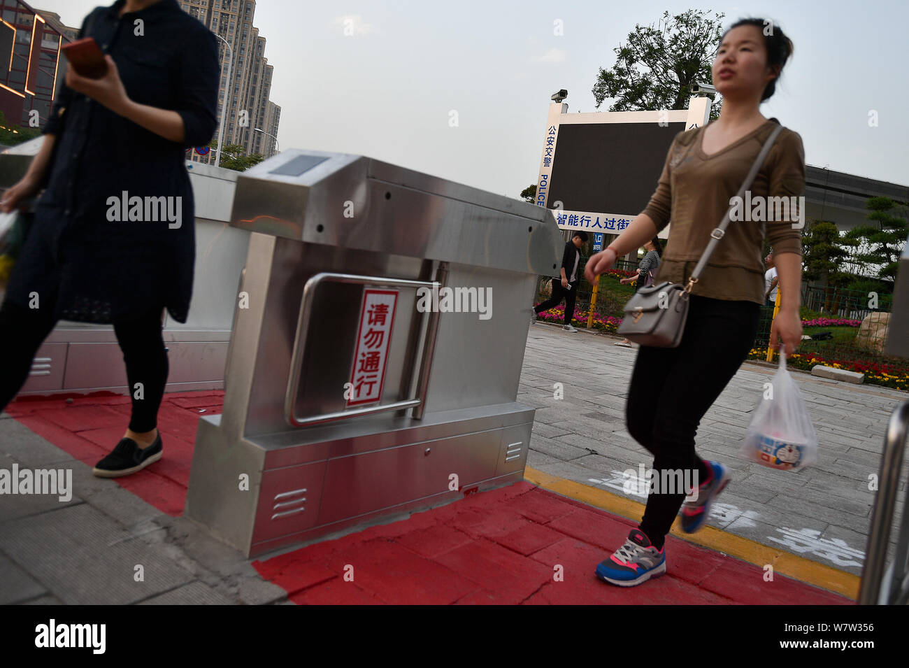 Pedestrians walk through newly installed crosswalk gates, which shut ...