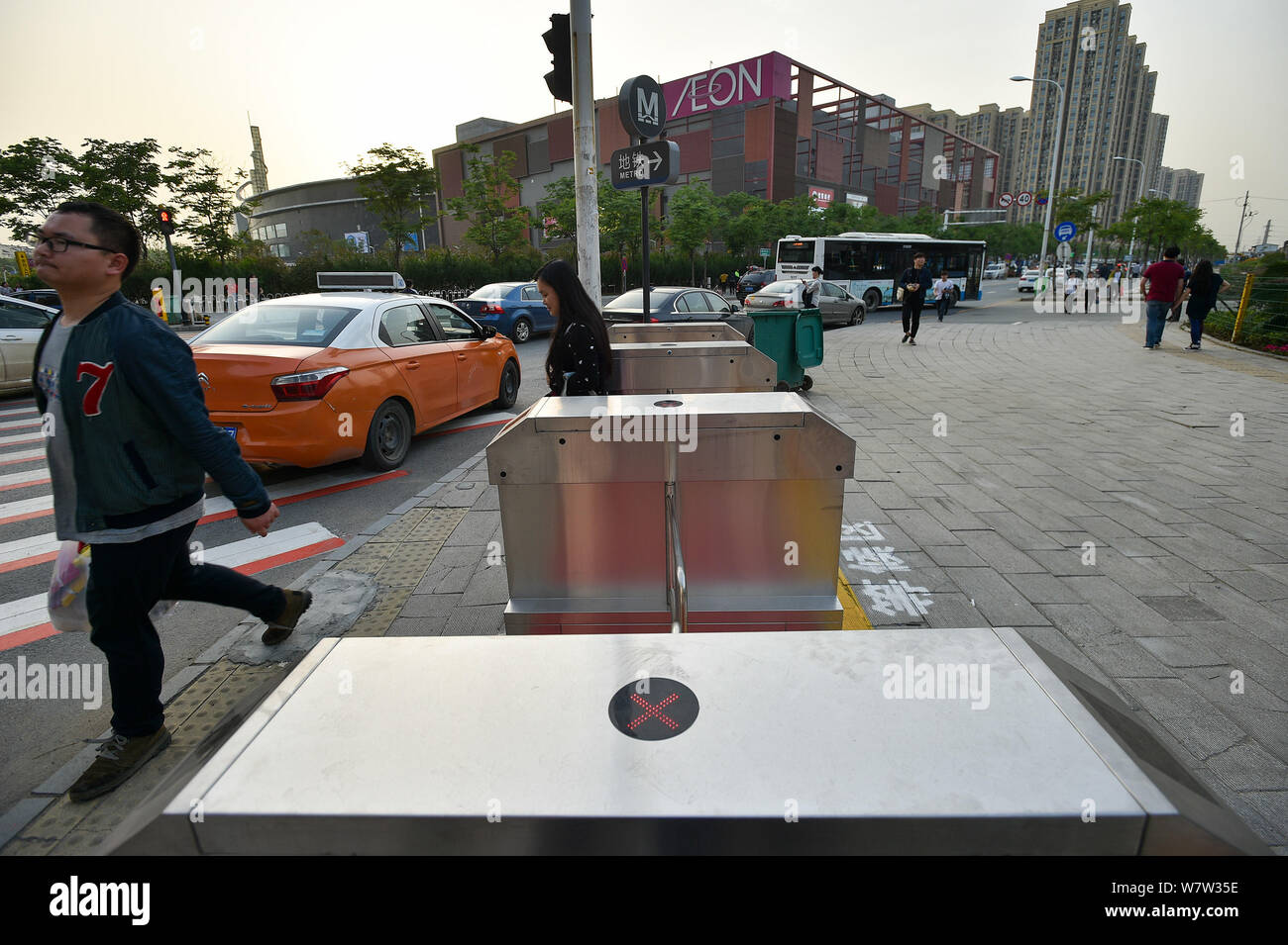 Pedestrians walk through newly installed crosswalk gates, which shut ...