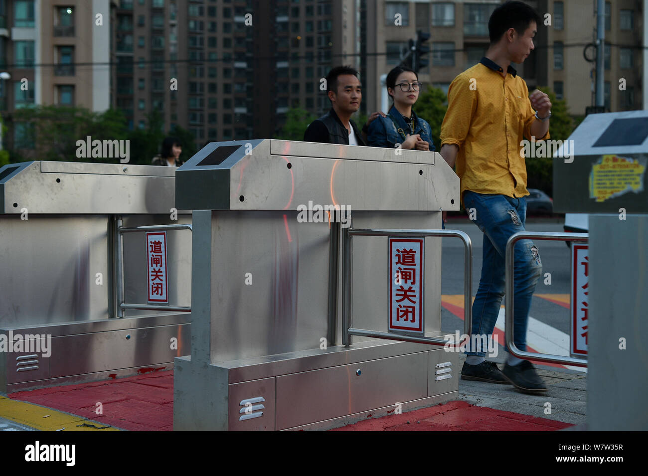 Pedestrians walk past newly installed crosswalk gates, which shut when ...
