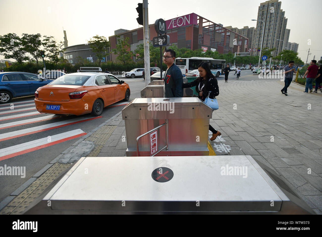 Pedestrians walk through newly installed crosswalk gates, which shut ...