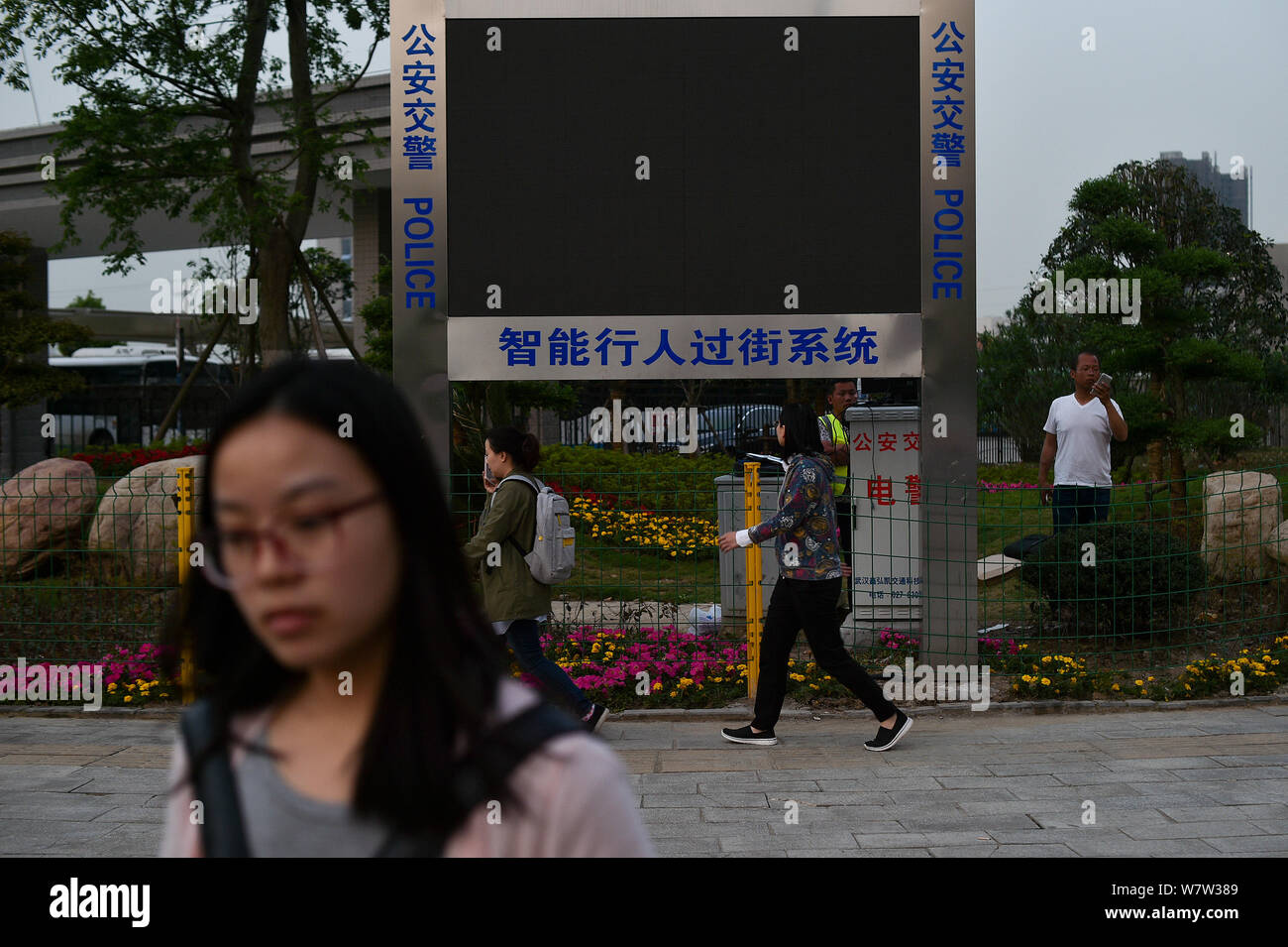 Pedestrians walk past a full-color LED screen to broadcast newly ...