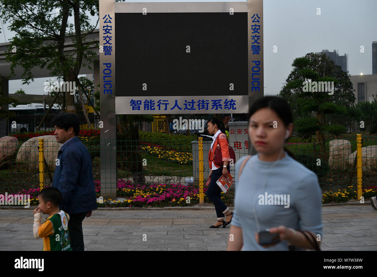 Pedestrians walk past a full-color LED screen to broadcast newly ...
