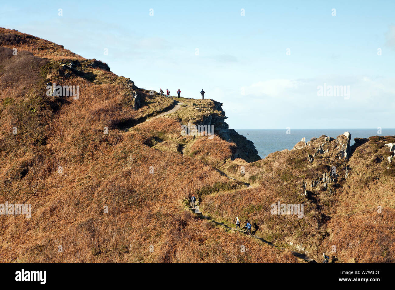 North Devon Coast Path near Pensport Rock, with walkers climbing up zig zag trail, west of ...