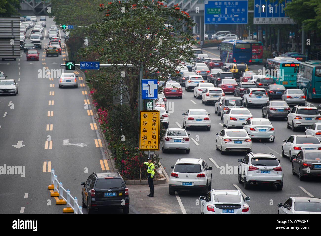 A traffic officer guides vehicles to drive on a reversible lane with a ...