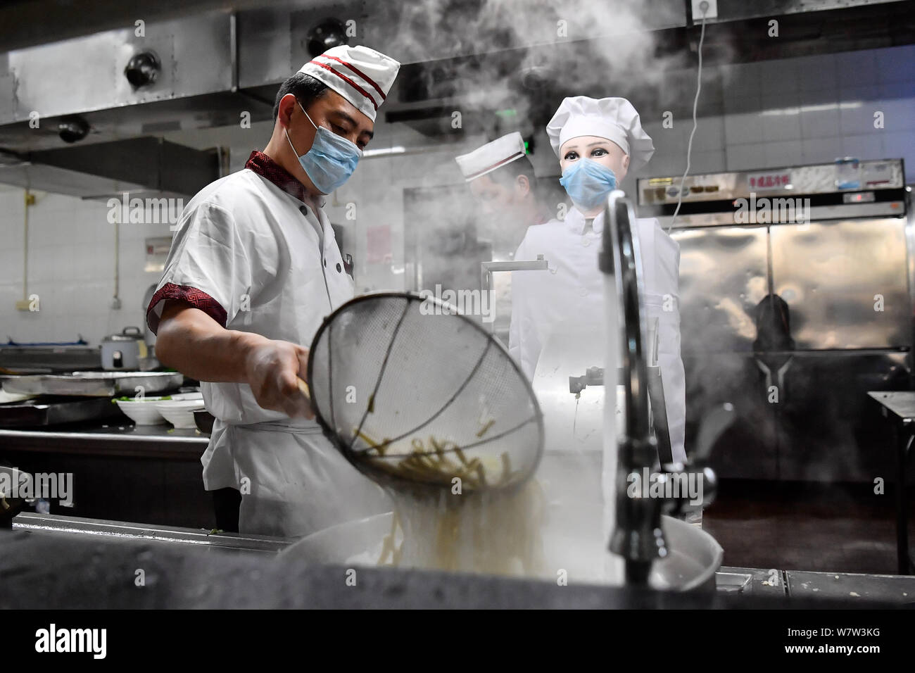Staffs drag for noodles sliced by the robot from boiling water at the ...