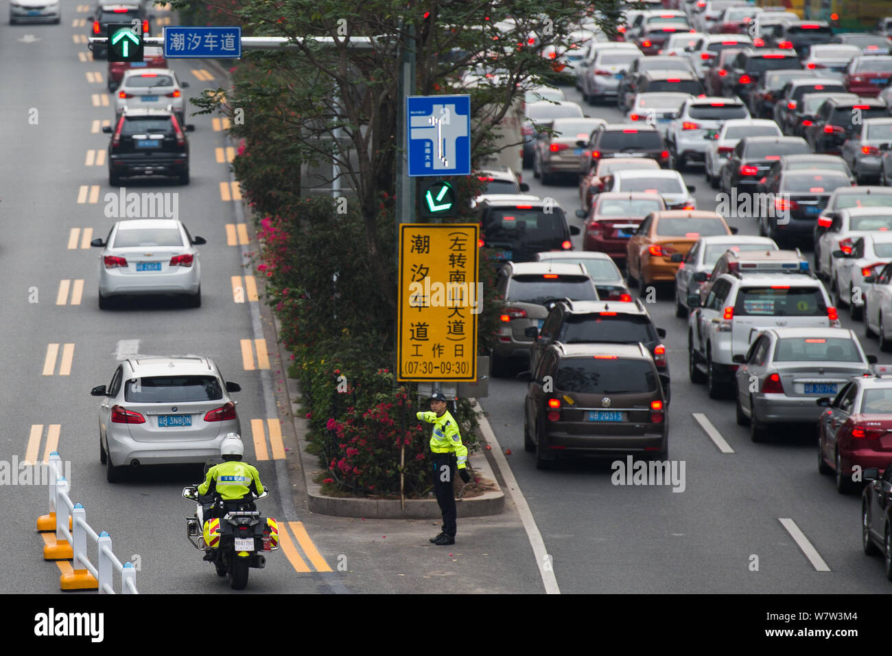 A traffic officer guides vehicles to drive on a reversible lane with a ...