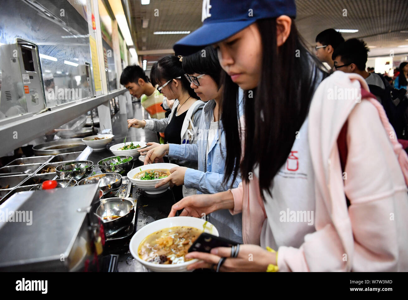 Students crowd to taste the noodles sliced by the robot at the canteen ...