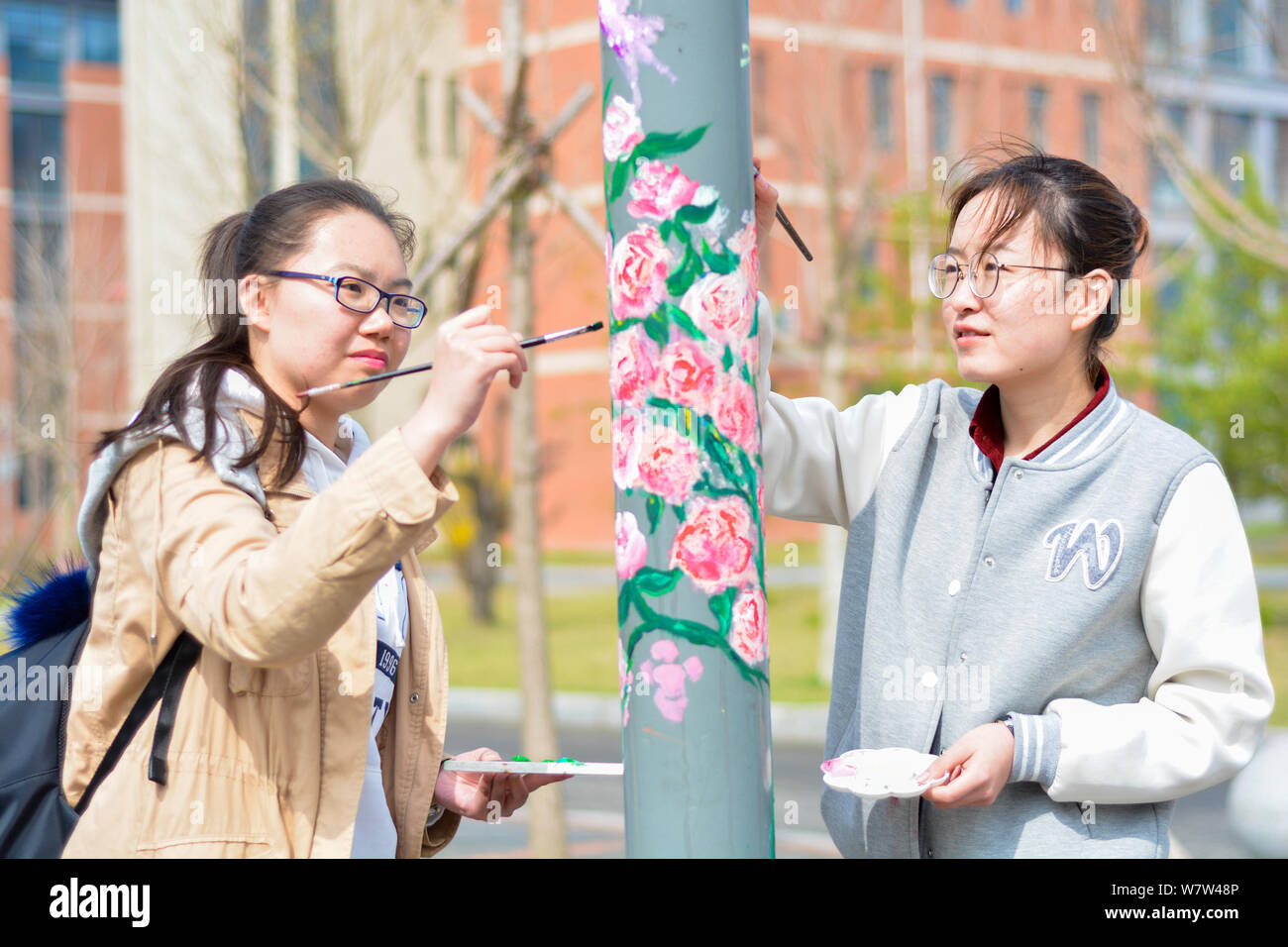 Chinese students paint a vivid drawing on a light pole around the ...