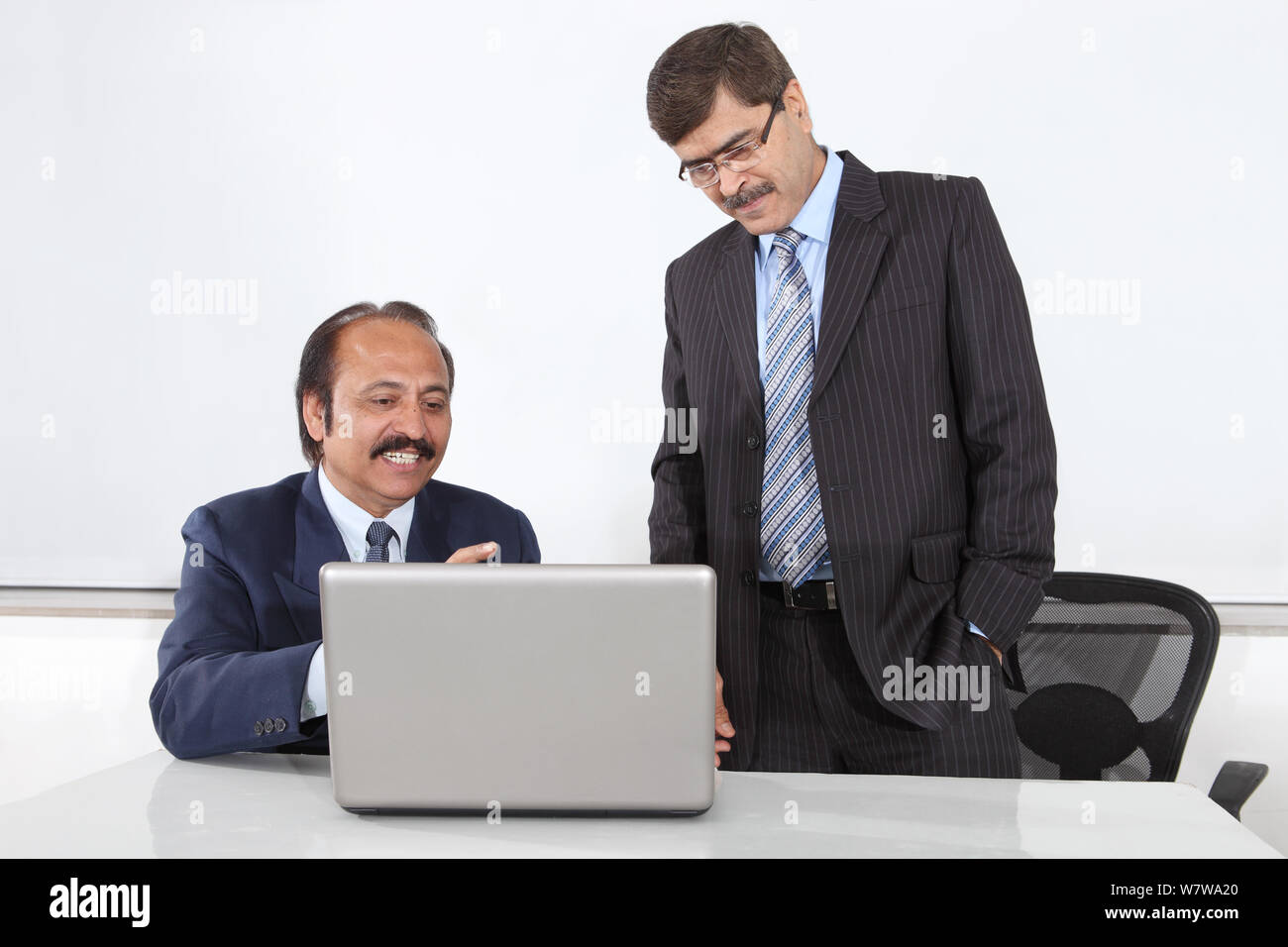 Two business executives working on a laptop in an office Stock Photo ...