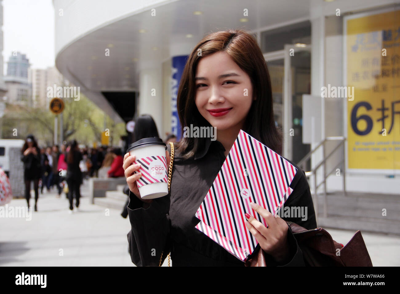 A trendy Chinese girl shows a cup of coffee she bought from the Coco ...