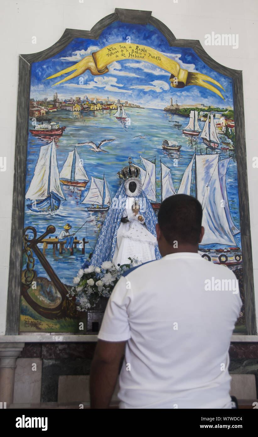 Man praying to the Virgen de Regla, the patron saint of the Afrocuban ...