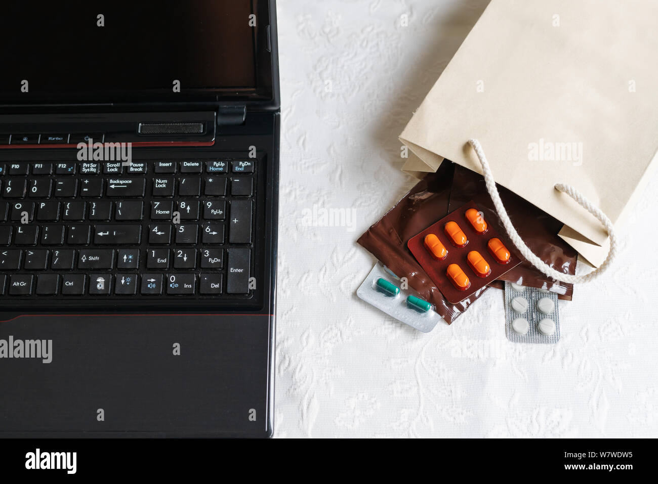 Medicines and pills next to laptop, notebook keyboard. Stress in the ...