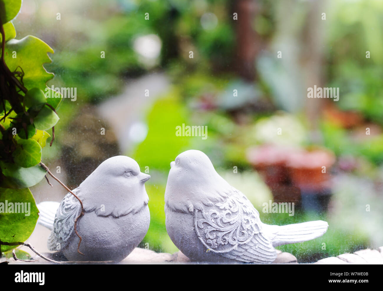 Couple birds, two white bird statues in garden through the window Stock ...