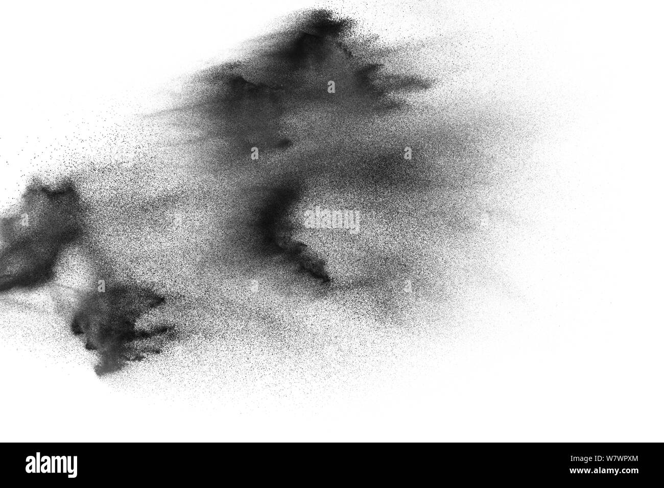Black sand explosion against white background.The particles of sand ...