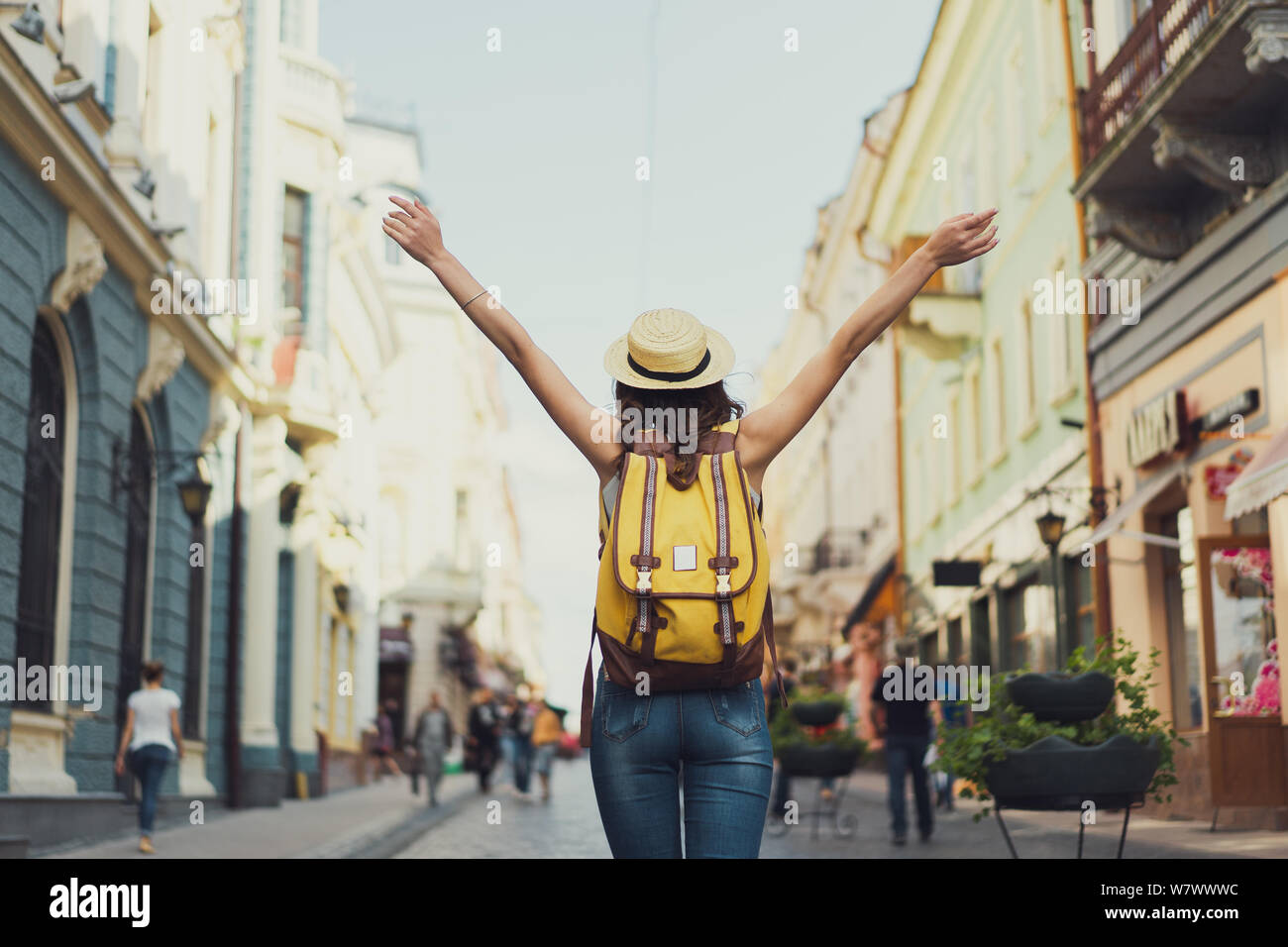 Back view of a young woman traveler with a backpack on her shoulder out ...