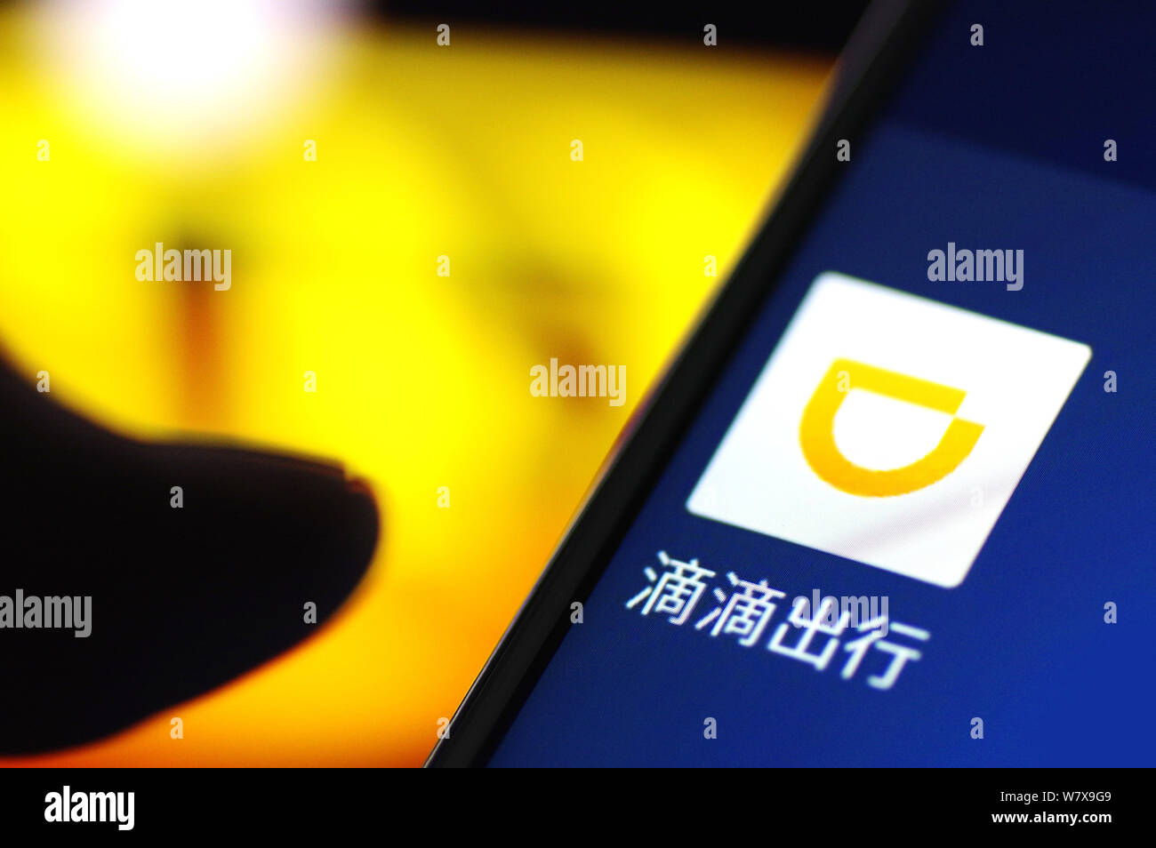 --FILE--A Chinese mobile phone user looks at the icon of taxi-hailing ...