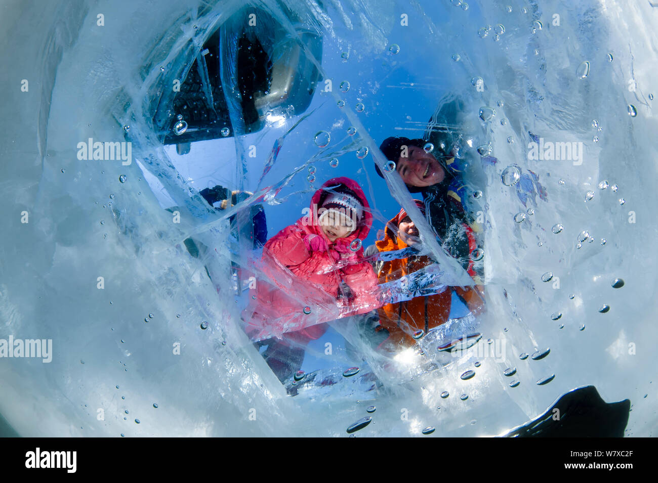 People looking through transparent ice (1m thick) on lake surface to ...