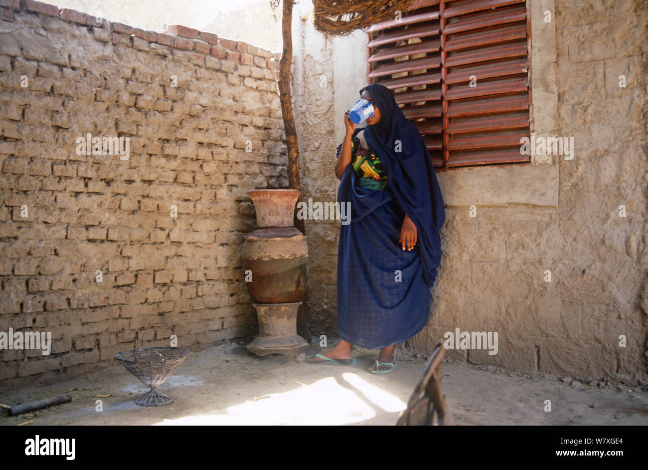 Woman drinking water stored in terracotta jar. N'Djamena, Chad, 2002 ...