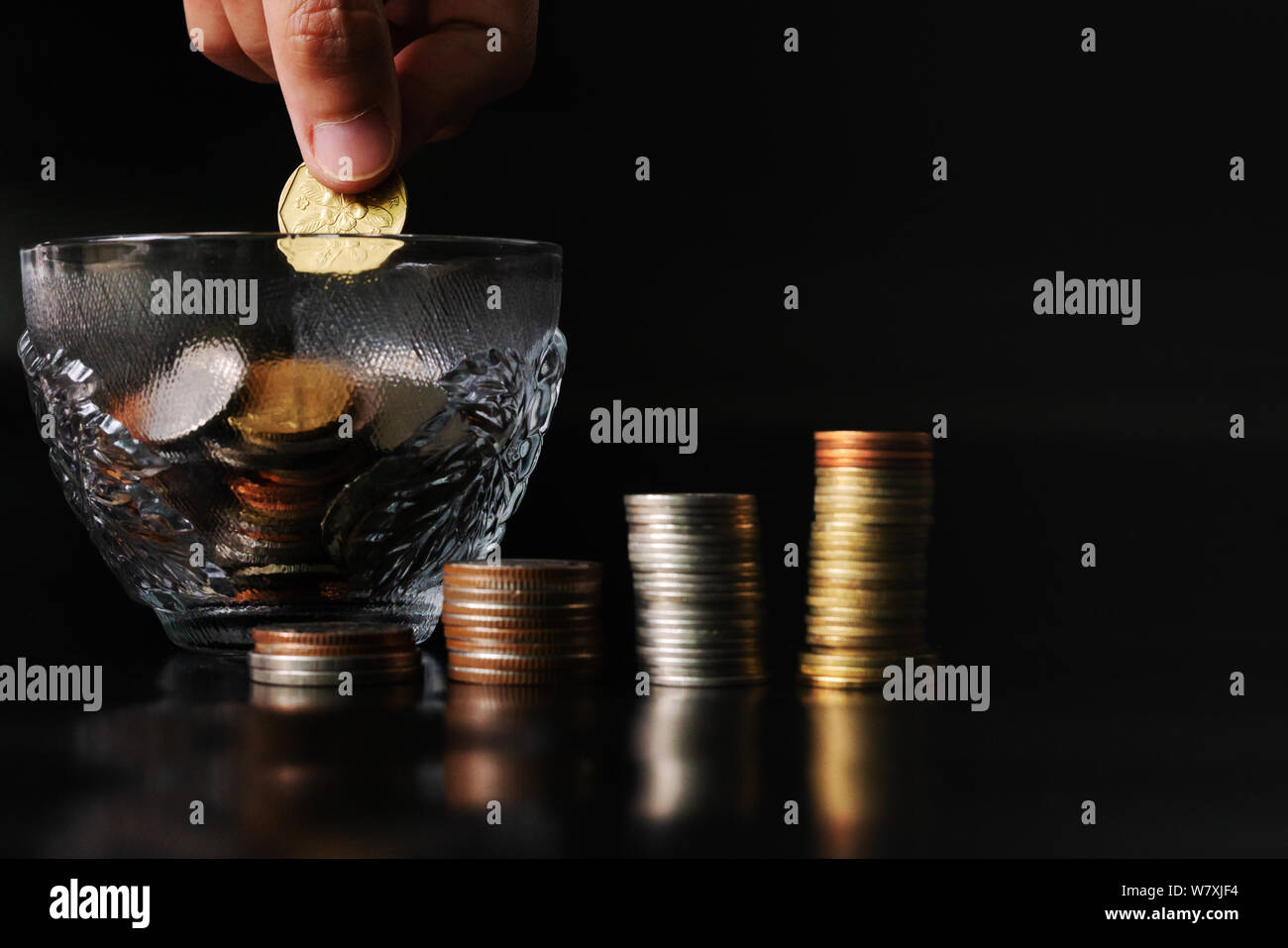 add saving coin to coin cup, money saving concept Stock Photo - Alamy