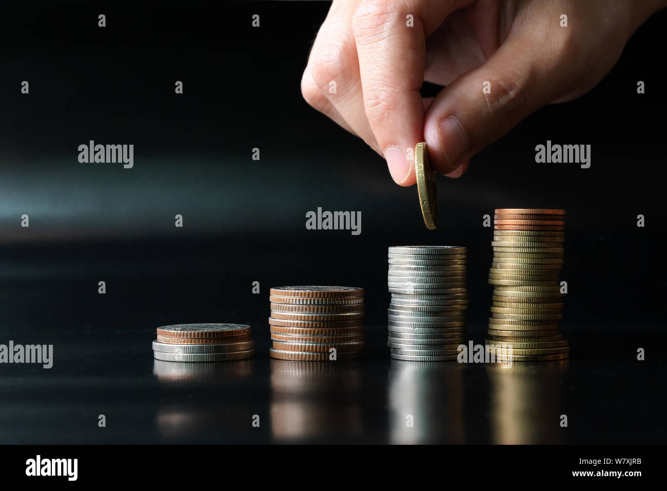 add saving coin to top of coin stack, money saving concept Stock Photo ...