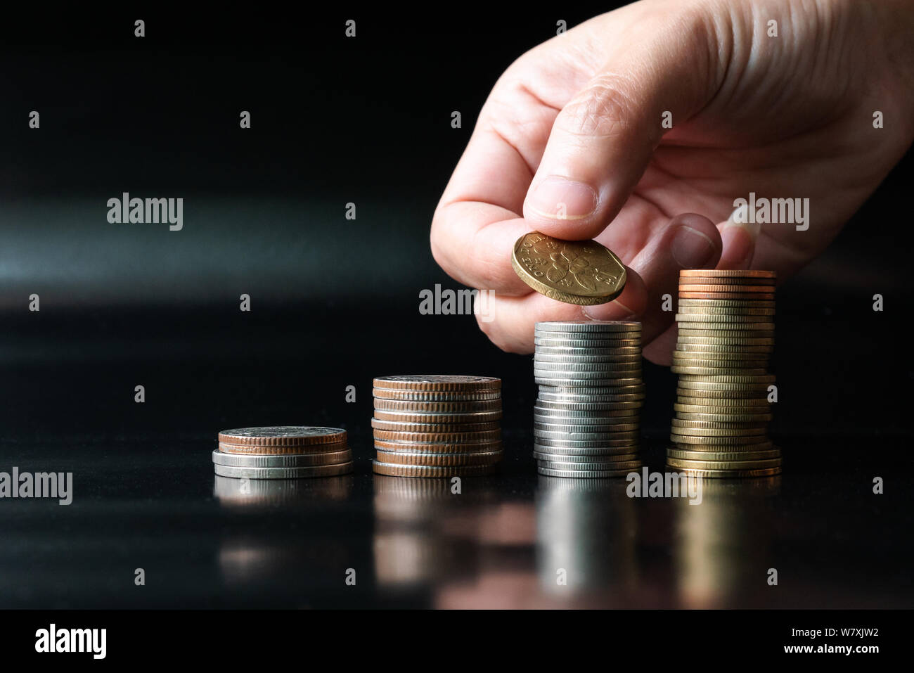 add saving coin to top of coin stack, money saving concept Stock Photo ...