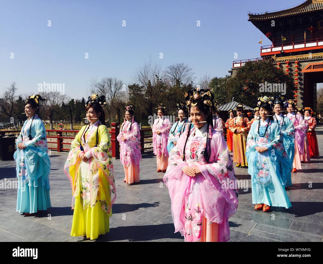 Chinese tour guides dressed in traditional Han costumes bite chopsticks ...