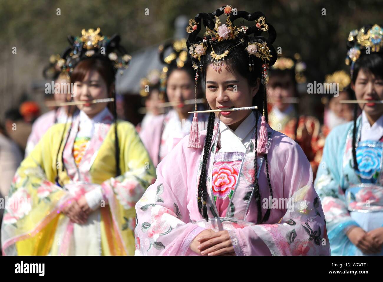 Chinese tour guides dressed in traditional Han costumes bite chopsticks ...
