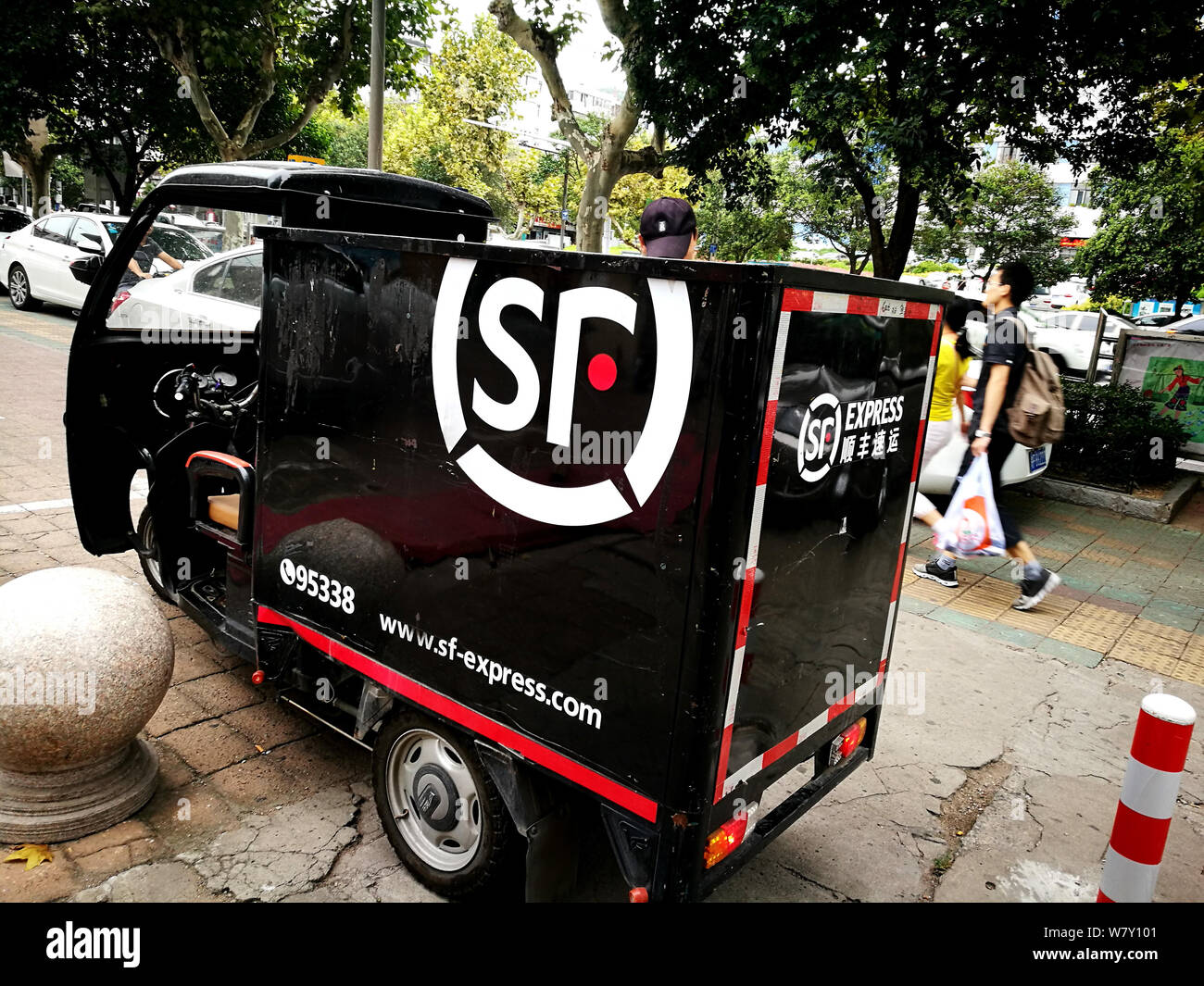 --FILE--A pedestrian walks past a delivery tricycle of SF Express on a ...