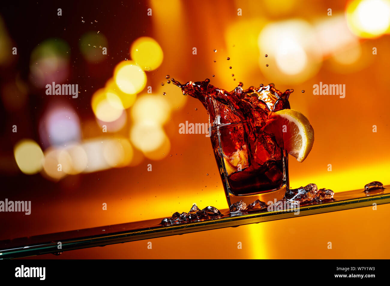 Slice of lemon falling into a glass of Cola. Cocktail with lemon. Copy ...