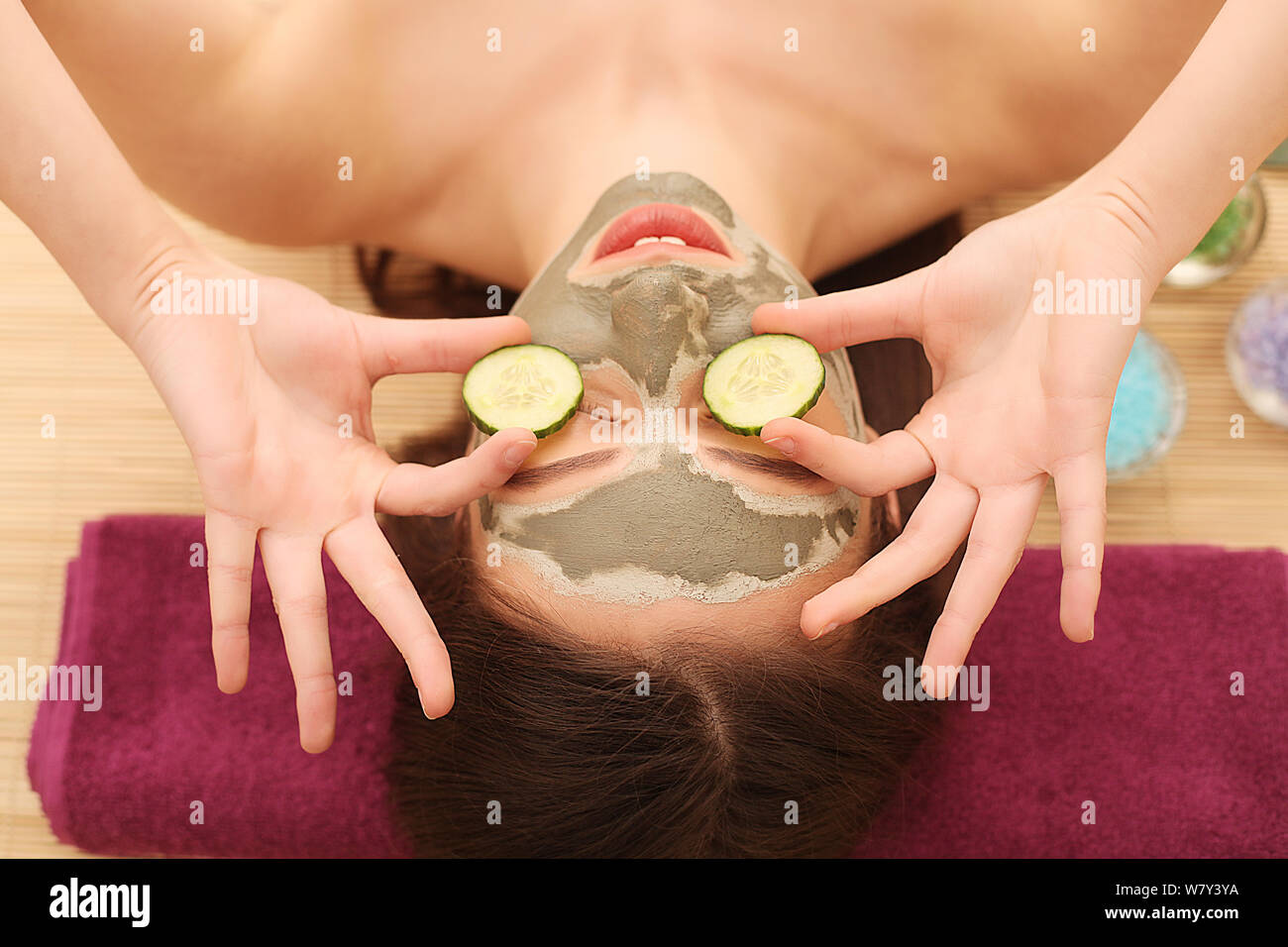 Spa. Care Facial. Funny young girl with a mask for skin face and cucumbers Stock Photo - Alamy