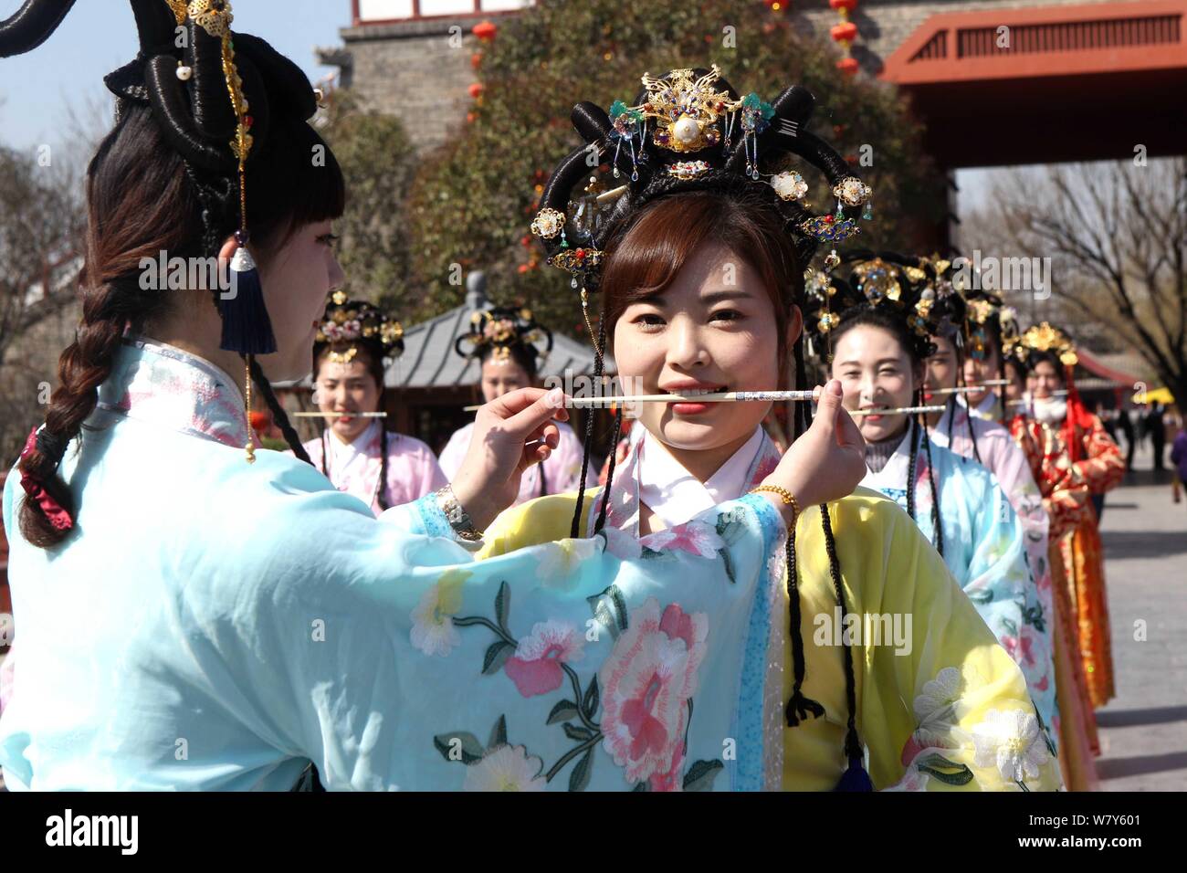 Chinese tour guides dressed in traditional Han costumes bite chopsticks ...