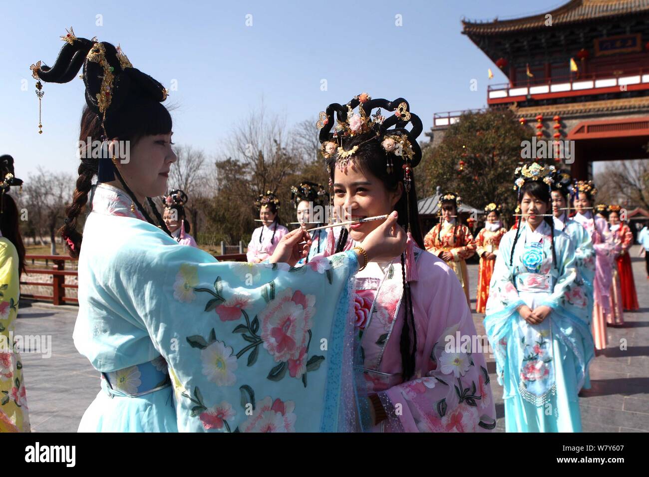 Chinese tour guides dressed in traditional Han costumes bite chopsticks ...