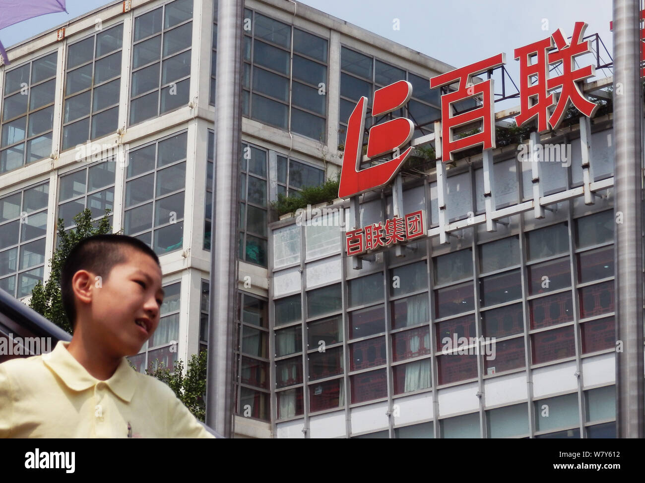 --FILE--A young boy walks past a logo of Bailian Group in Shanghai ...
