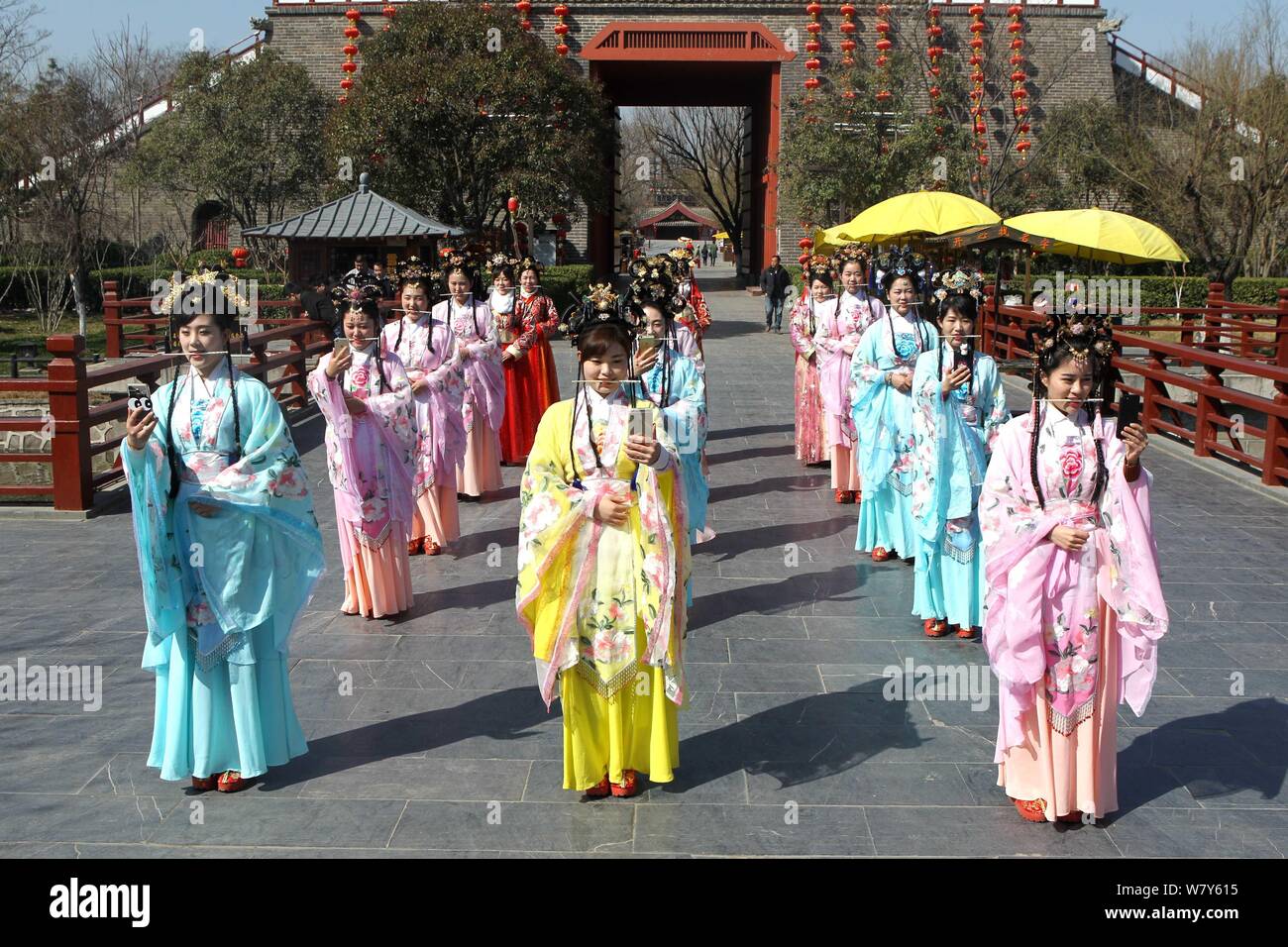 Chinese tour guides dressed in traditional Han costumes bite chopsticks ...