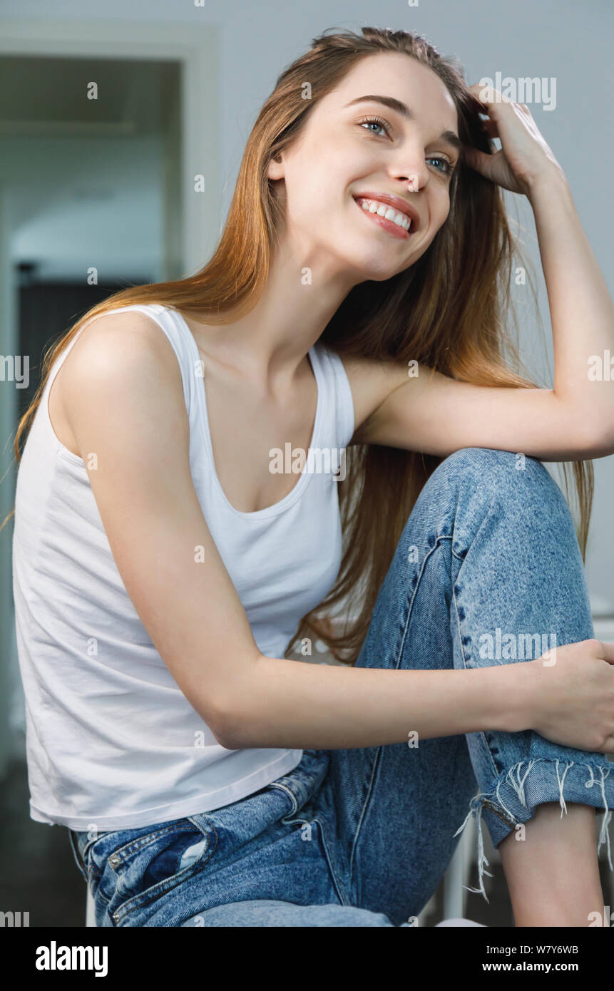 Happy positive girl sitting on the chair at the kitchen and dreaming ...