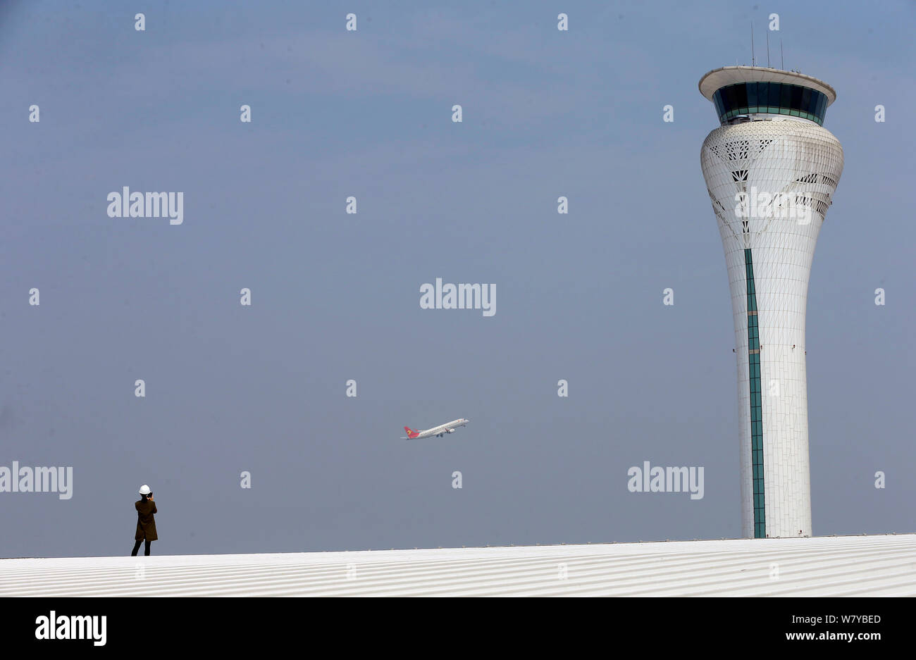 A Chinese employee takes photos of a jet plane taking off next to the ...