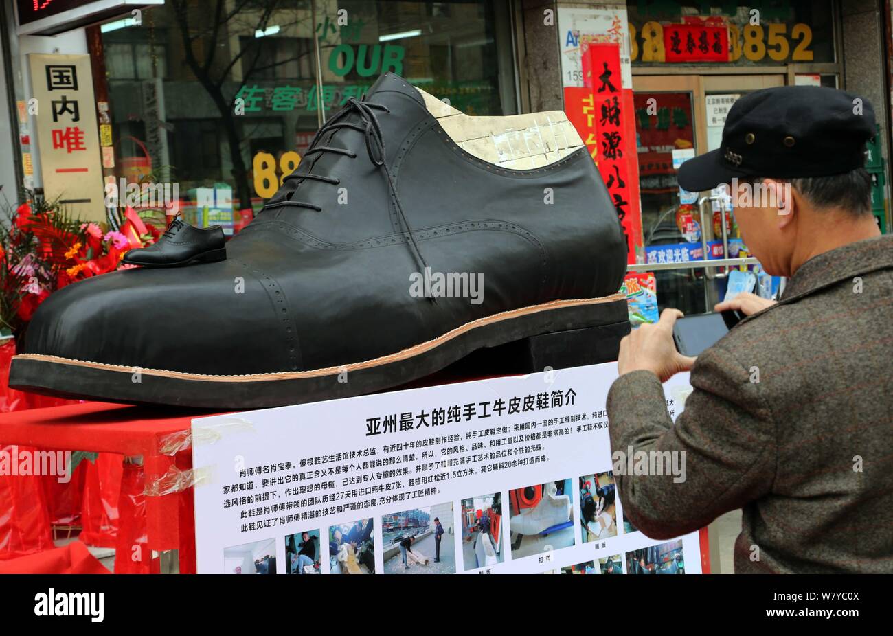 A pedestrian takes photos of the giant shoe on display in Shenyang city ...
