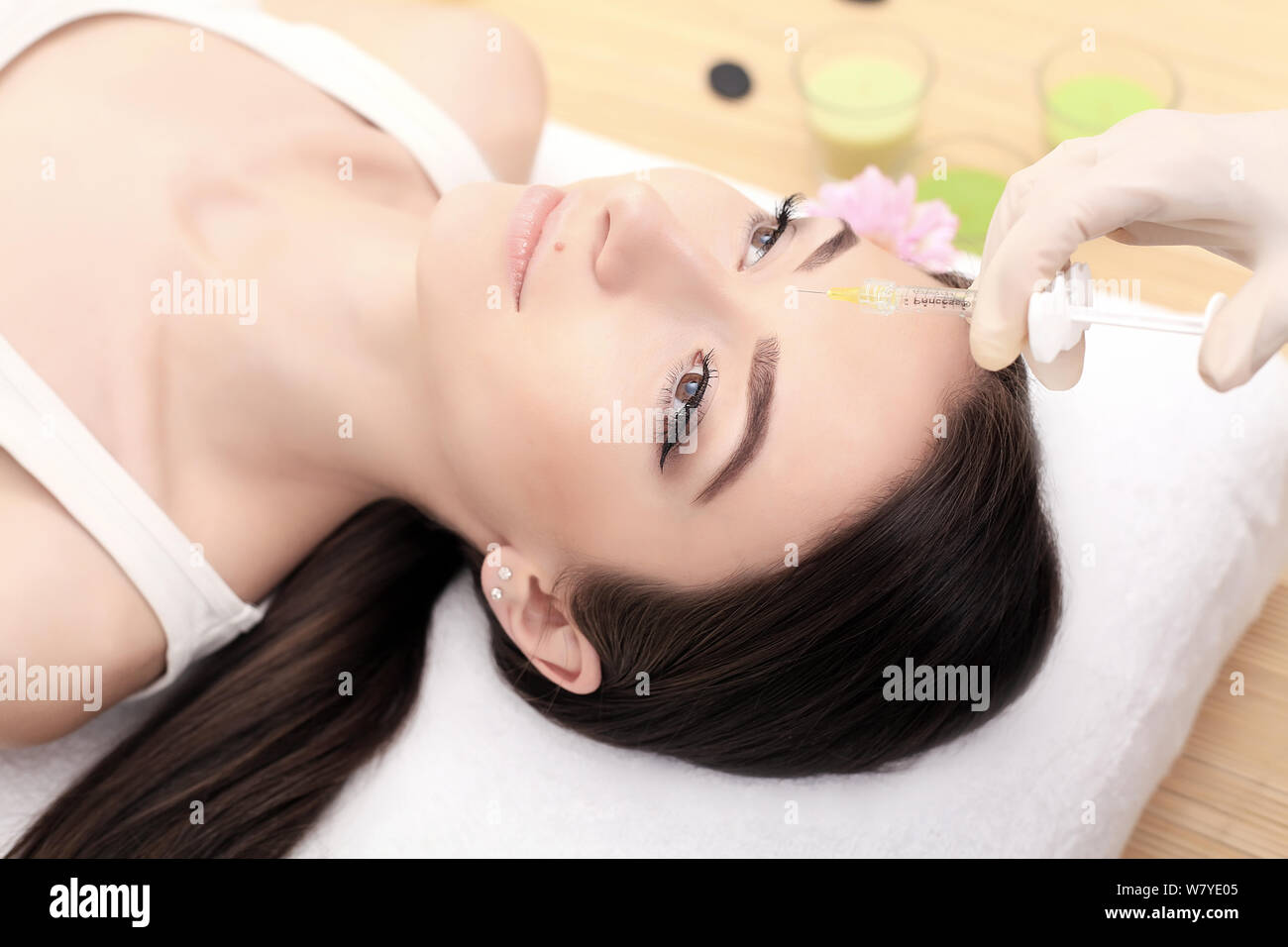 Hands of cosmetologist making injection in face. Young woman gets ...