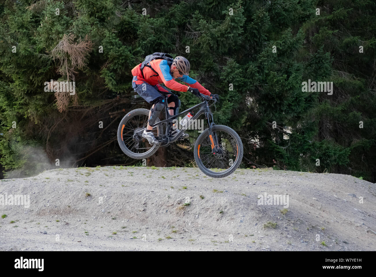 Mtb biker jumping on a dusty jump Stock Photo - Alamy