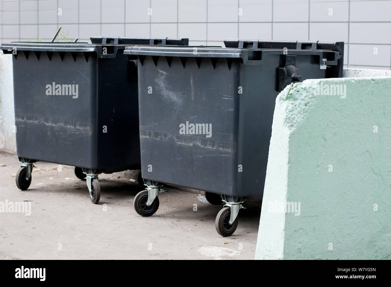 Garbage bins near housing block. Dumpsters on the grey wall background ...