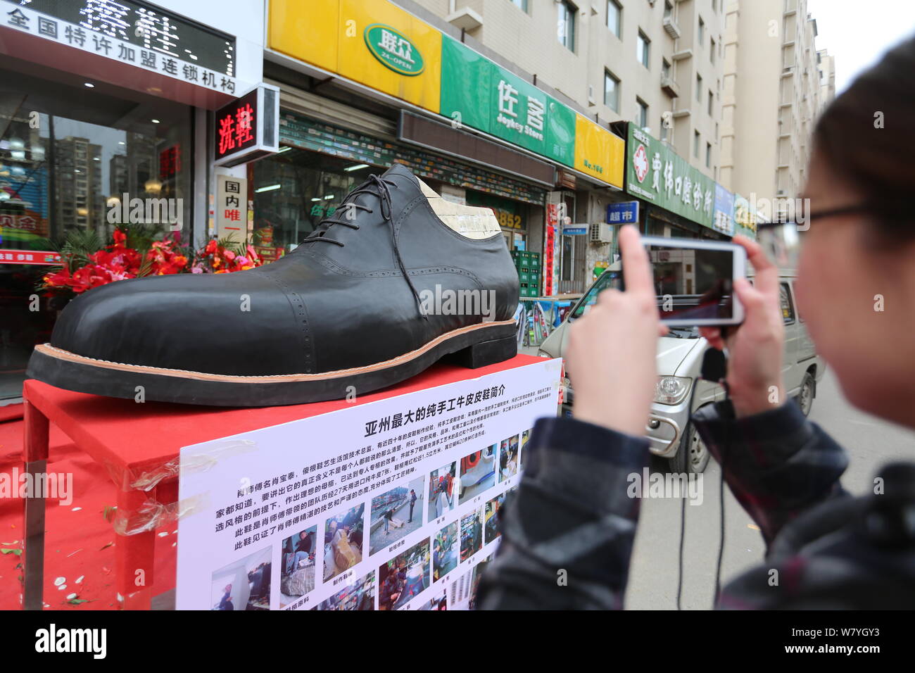 A pedestrian takes photos of the giant shoe on display in Shenyang city ...
