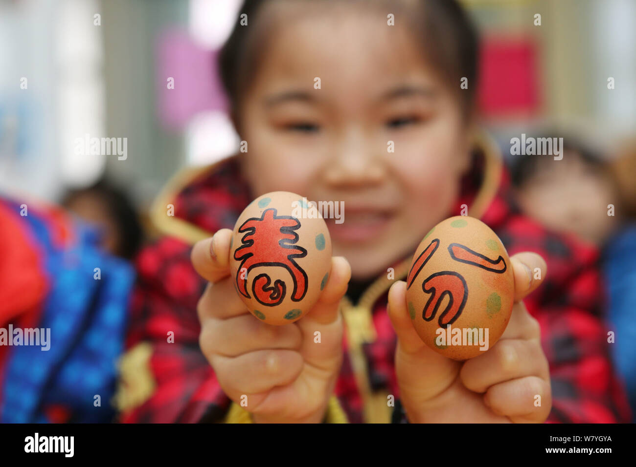 A Chinese kid shows the eggs painted with Chinese characters for ...