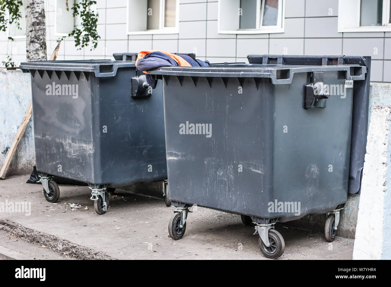 Garbage bins near housing block. Dumpsters on the grey wall background ...