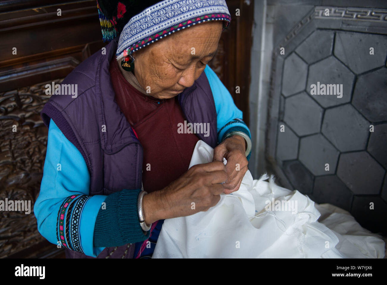 A Chinese female elder of the Bai ethnic group ties sections of a white ...