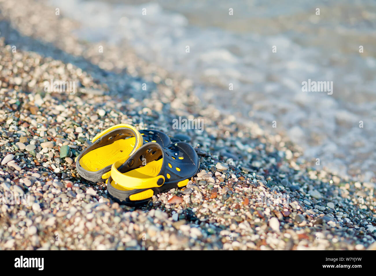 pair of kid's sandals of a swimmer in a beach near by the sea at summer ...