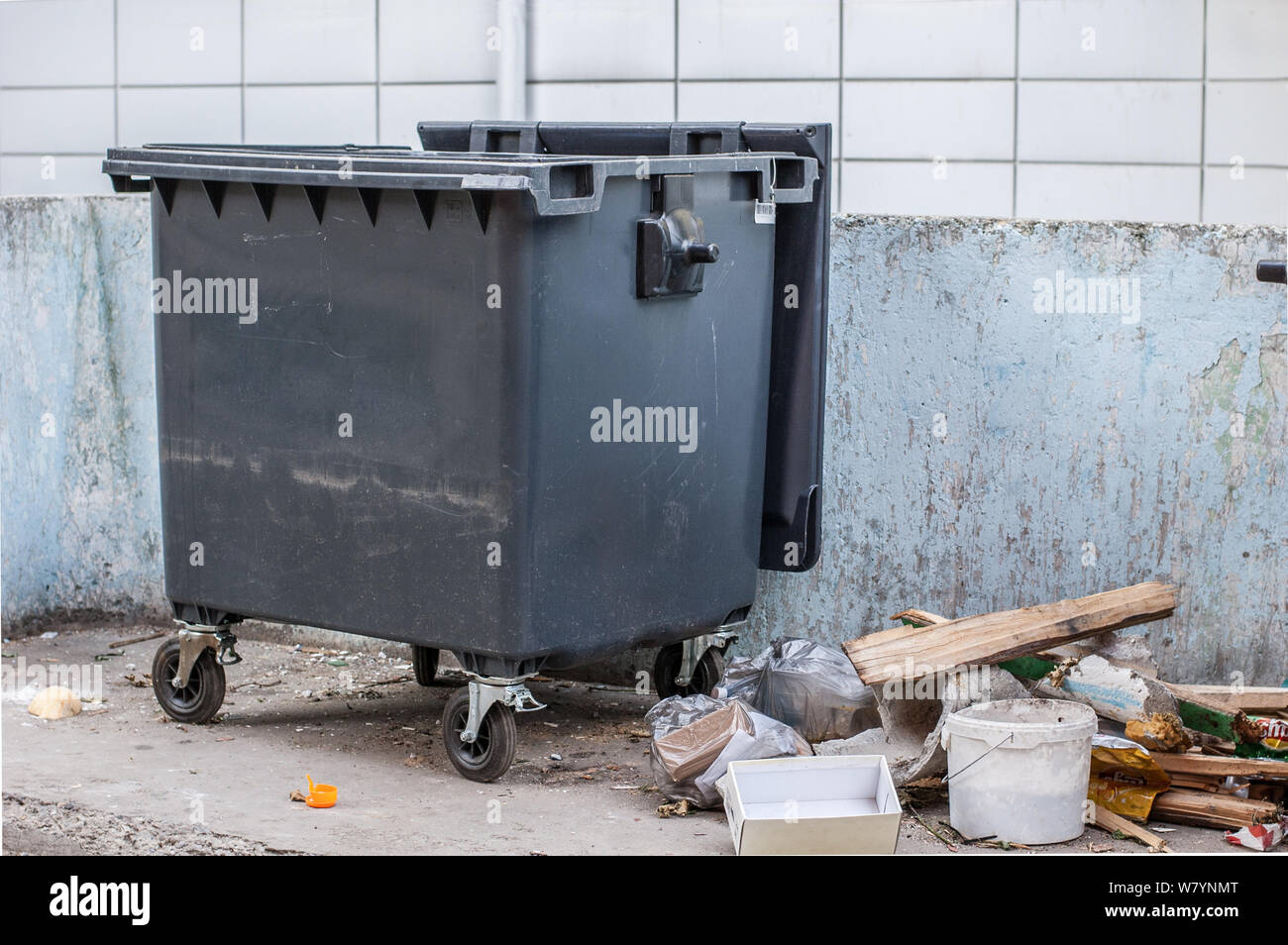 Garbage bin near housing block. Dumpster on the grey wall background ...