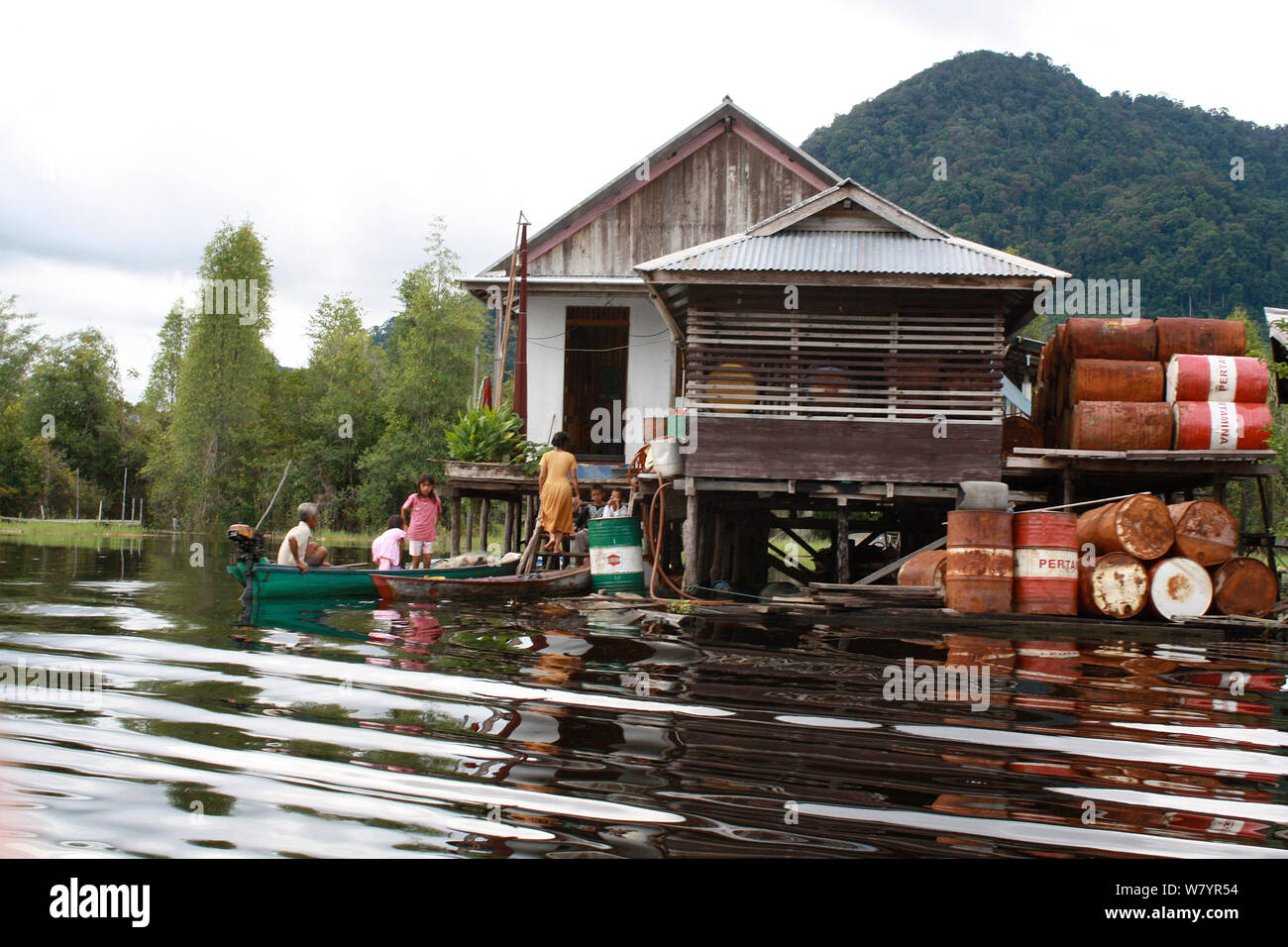 Dayak house outside of river, with palm oil barrels outisde house ...