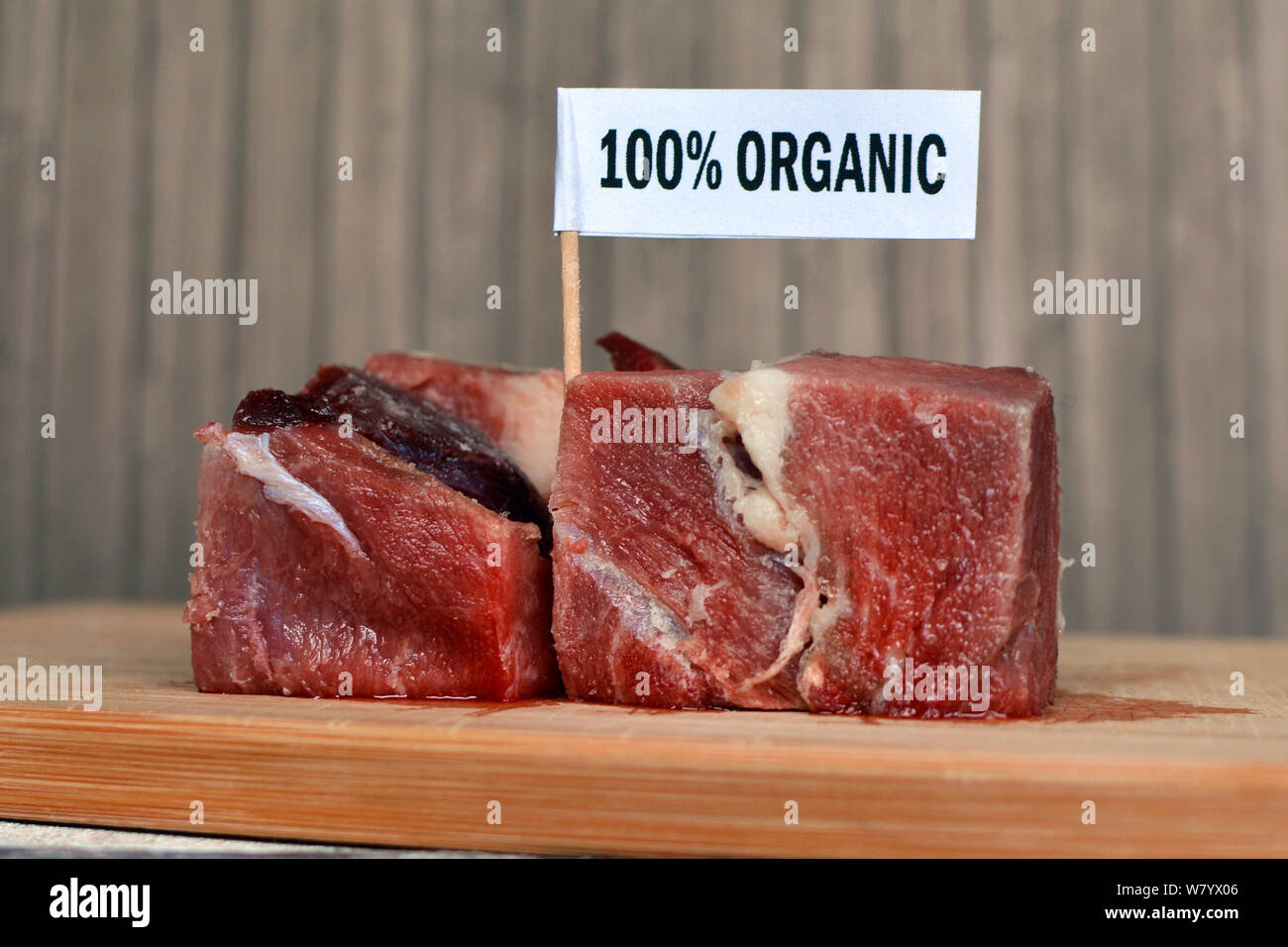 Big raw red meat chunks on wooden plate with label saying '100 percent ...