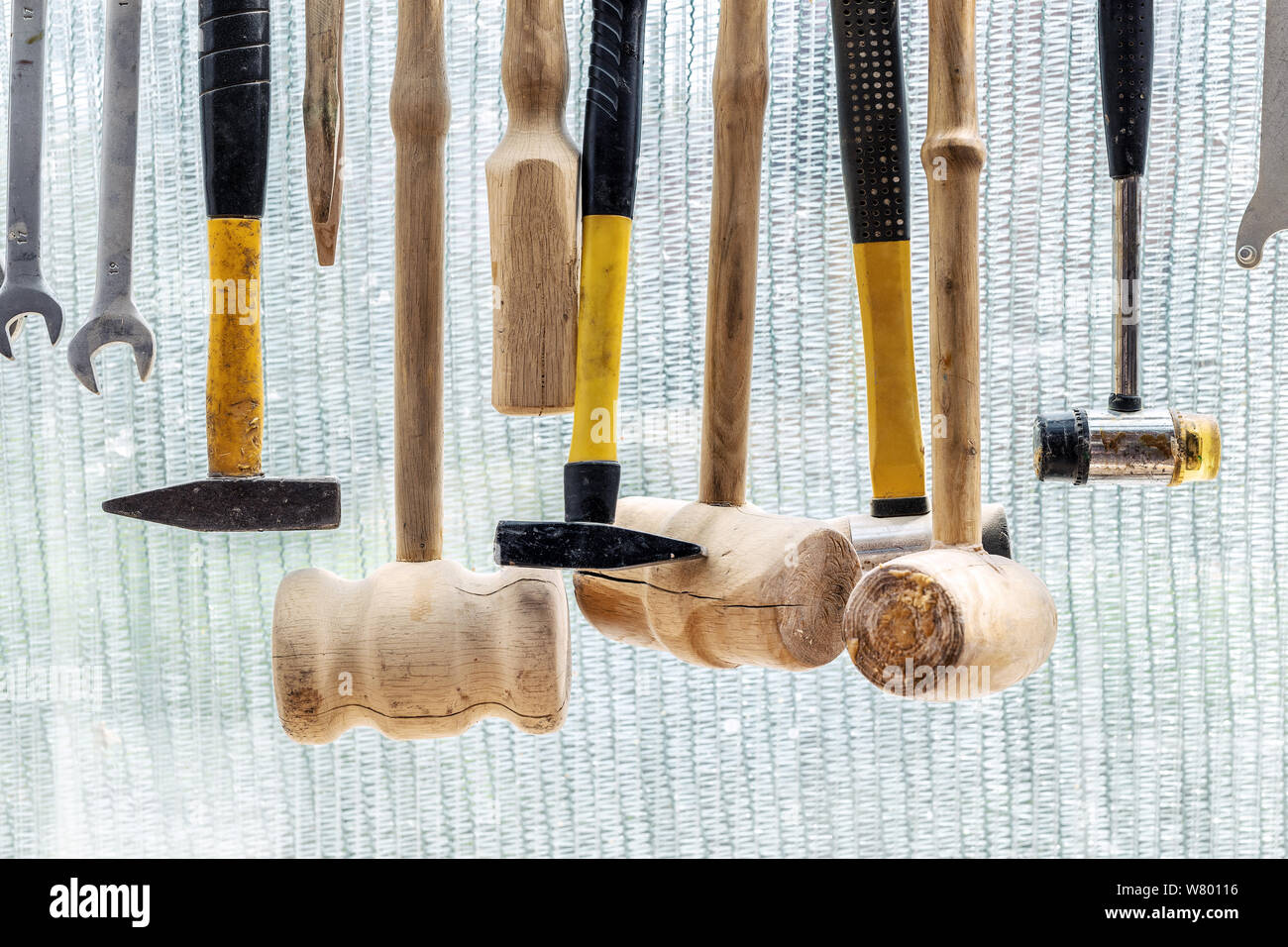 Set of different purpose hammers and tools hanged on wall against ...